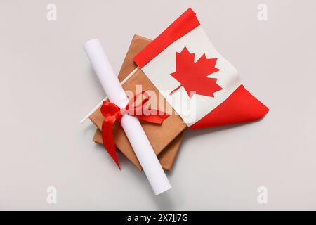 Diploma with red ribbon, books and Canadian flag on white background ...
