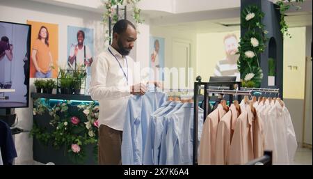 Employee restocking luxurious clothing store with elegant assortment of ...