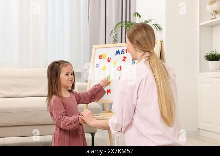 Mom teaching her daughter alphabet with magnetic letters at home Stock ...