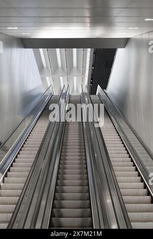 An empty escalator in a modern subway station with brick walls and ...