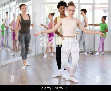 Teenage girl and boy practicing plie position of ballet in dance studio ...