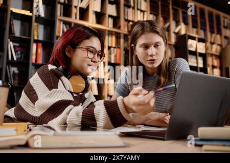two asian girls discussing college assignments while meeting in cafe ...