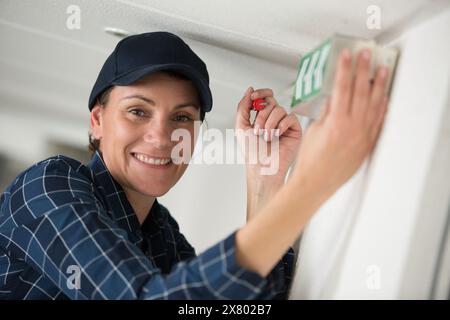 female contractor installing illuminated exit sign Stock Photo - Alamy