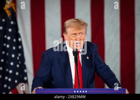 Donald Trump speaks on stage using a hand gesture at the sides of his ...
