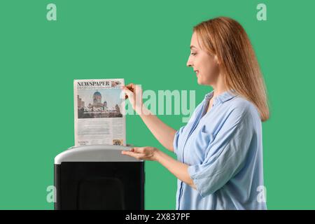 Adult woman pointing at newspaper and shredder on green background ...