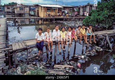 Philippines, Davao; children sit on a plank in a flooded slum Stock ...