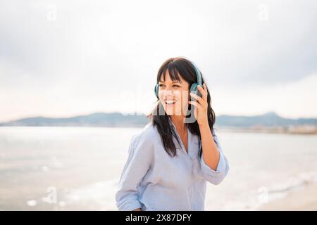 Happy Black woman enjoying music with headphones and smartphone ...