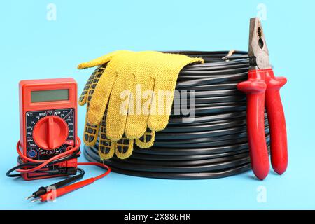 Multimeter, electric cable reel and gloves on color background Stock ...