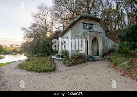 The sun setting behind the Gothic Cottage at Stourhead Gardens in ...