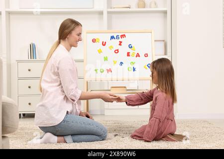 Mom teaching her daughter alphabet with magnetic letters at home Stock ...