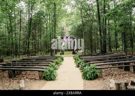Outdoor wedding ceremony setup in a forest with a purple-draped altar ...
