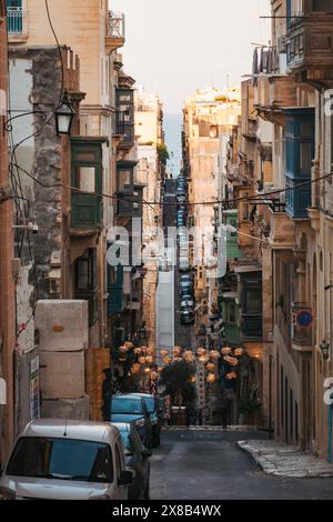 A city street with sloped terrain featuring parked vehicles and ...
