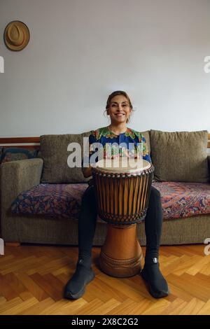 A percussionist Adult Latin Woman is Happy posing with her Djembe drum ...