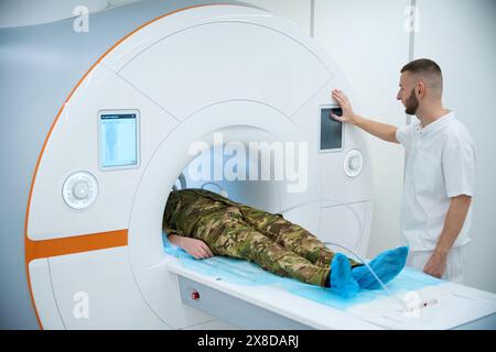 Technologist preparing man for magnetic resonance imaging of lower ...