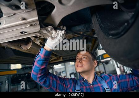 Man performing maintenance on chassis of machine Stock Photo - Alamy