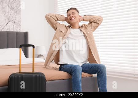 Guest stretching in stylish hotel room, focus on suitcases Stock Photo ...