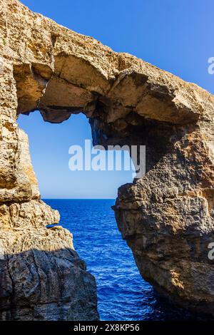 Majestic ancient rock arch on coastal cliff, clear blue sky, serene ...
