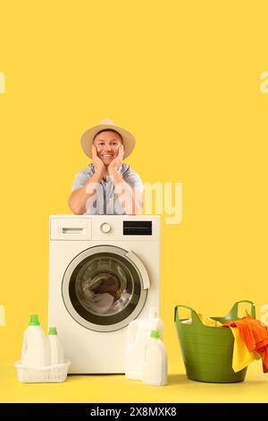 Young man leaning on a washing machine and pointing isolated on white ...