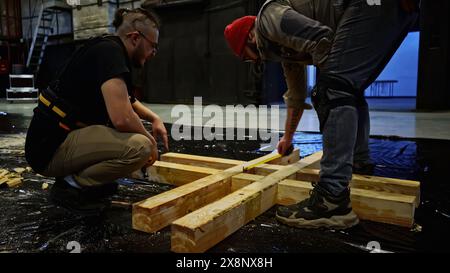 Assembly of wooden stage construction by young builders. Media. Men ...