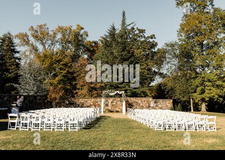Outdoor wedding ceremony setup with white chairs and floral aisle Stock ...