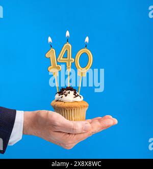 Birthday cupcake with number 140 candle - Orange color background Stock Photo - Alamy