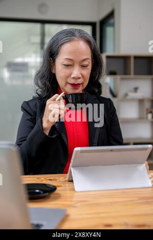 Sipping on success. a mature businesswoman drinking tea while working ...