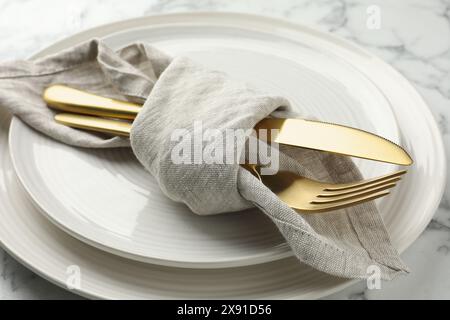 Plates and cutlery on white marble table, closeup Stock Photo - Alamy