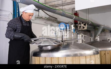 Portrait of brewer who is making beer on his workplace in the brew ...