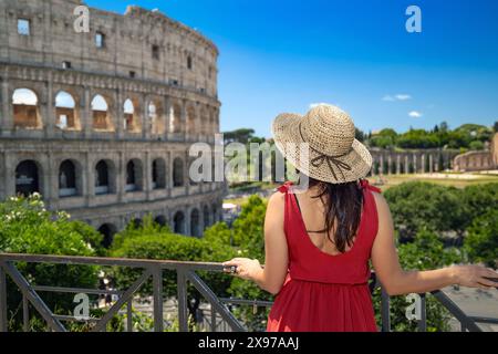 Brunette girl with straw hat admires the majesty of the Colosseum and ...