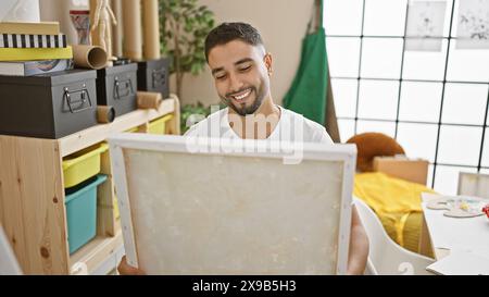 Handsome man with beard holding brushes close to easel stand smiling ...