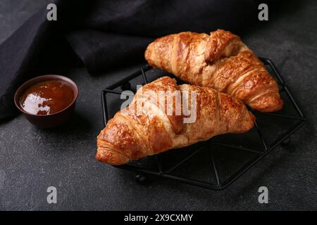 Stand with tasty croissants and bowl of jam on black background Stock ...