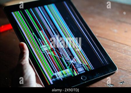 A broken tablet with a colorful, distorted screen and two disassembled ...
