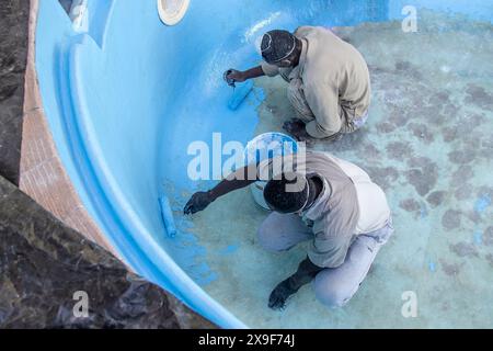 Workmen using rollers to apply fibreglass gel coat paint to an old ...