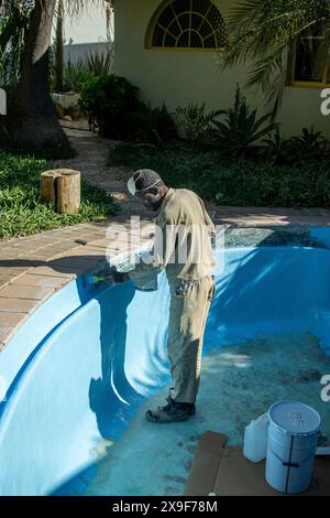 Workman using a paintbrush to apply fibreglass gel coat paint to an old ...