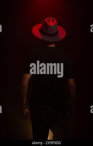 Mysterious man wearing hat standing with his back to the camera. Studio ...