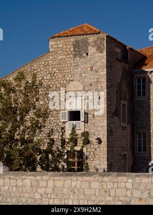 Stone building with red shutters against a mountain backdrop Stock ...