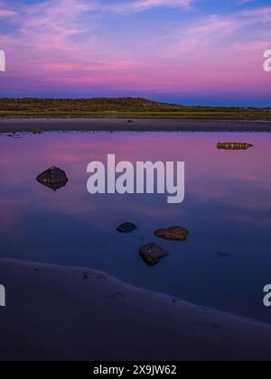 Sunset casts a pink glow over the rugged Serra des Cavall Bernat cliffs ...
