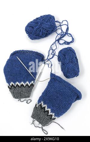 Flat lay photography of a blue wool yarn knitting on the metal needles ...