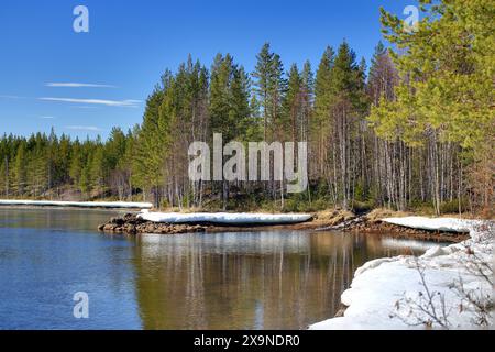 Frozen riverside of Skellefte river under blue sky in northern Sweden ...