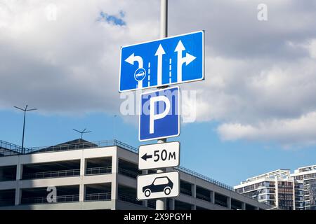 A sign pointing to parking located on a post next to a fence with a ...