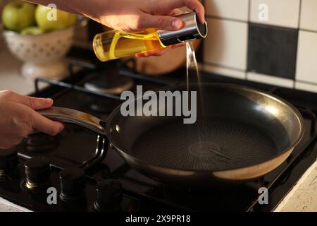Vegetable fats. Woman sprinkling oil into frying pan on stove in ...