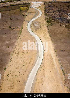 Aerial view of a winding, S shaped road through a sandy, dry landscape ...