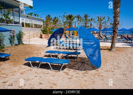 Old sunbeds and beach umbrellas in greek hotel before the start of the ...
