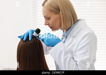 Trichologist with dermatoscope examining patient`s hair in clinic ...
