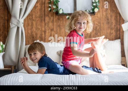 Cute sweet toddler children, tickling feet on the bed, laughing and ...