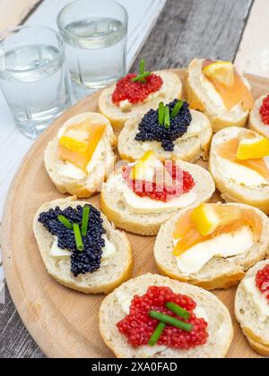 A closeup of assorted fish roe appetizers and glasses of vodka on the ...