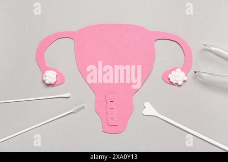 Paper uterus with gynecological speculum and pap smear test tools on ...