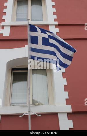 greek flag waving in front of the belltower of poros, greece ...