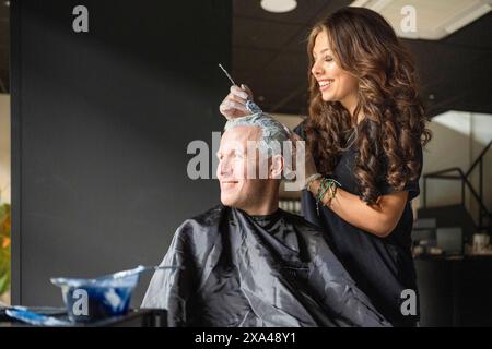 Hairdresser applying highlights to client's hair at a beauty salon ...