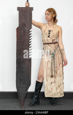 A female cosplayer in a horror outfit posing with a large blade sword ...
